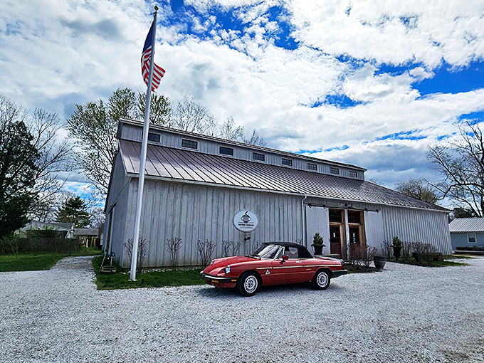 The Classic Motor Museum's weathered barn exterior houses automotive treasures inside, while a cherry-red Alfa Romeo Spider teases what awaits curious visitors.