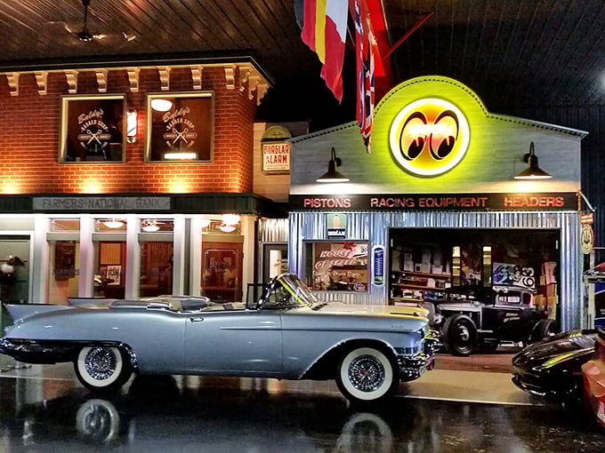 Step into automotive heaven where vintage storefronts and gleaming classics create a time-traveling wonderland. That blue convertible looks ready for a sunset cruise down memory lane.