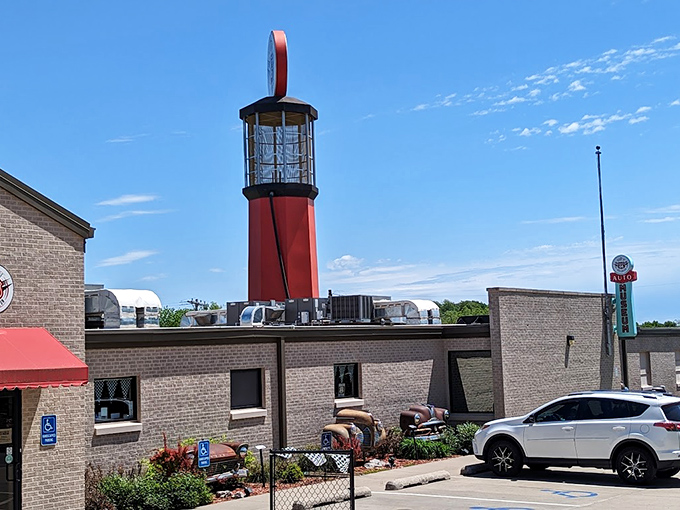 The museum's exterior features a striking lighthouse-style gas pump tower and vintage car parts artfully incorporated into the landscaping&mdash;automotive archaeology at its finest!