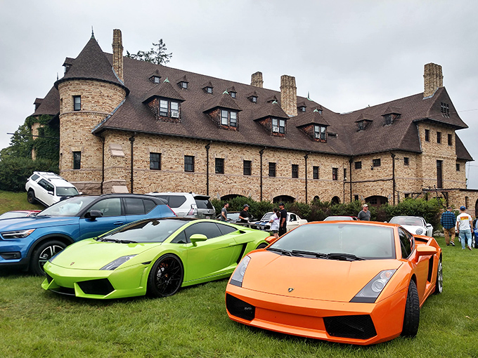 The castle-like exterior of Larz Anderson Auto Museum stands majestically against a blue sky, while a modern yellow Porsche offers a striking contrast to the historic stone facade.
