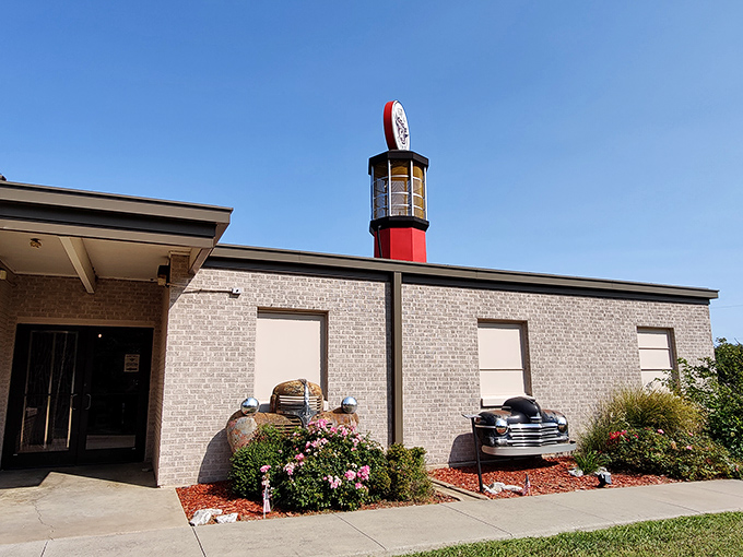 The museum's exterior features a striking lighthouse-style gas pump tower and vintage car parts artfully incorporated into the landscaping&mdash;automotive archaeology at its finest!