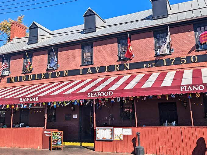 The historic red brick facade of Middleton Tavern stands proudly since 1750, its striped awning beckoning like a culinary time machine to colonial Annapolis.