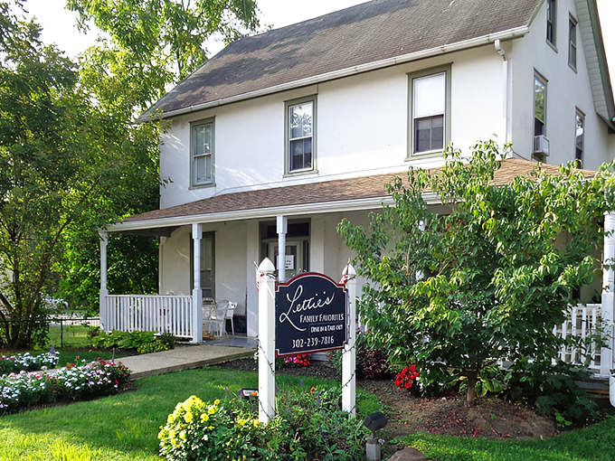 The white farmhouse with blue trim and wrap-around porch isn't trying to be fancy, but that rooster sign is basically saying "chicken paradise ahead!"