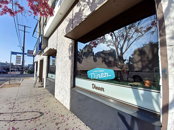 The iconic teal sign of Clark Street Diner beckons from beneath a Hollywood apartment building like a neon promise of comfort food salvation.