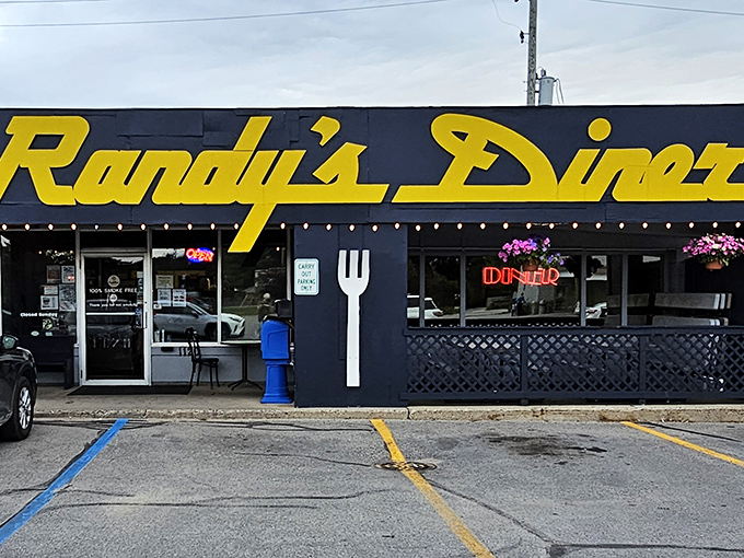 The iconic navy blue exterior with bright yellow lettering announces Randy's Diner like a beacon for breakfast lovers. That giant fork on the wall? It's pointing you toward hash brown nirvana.