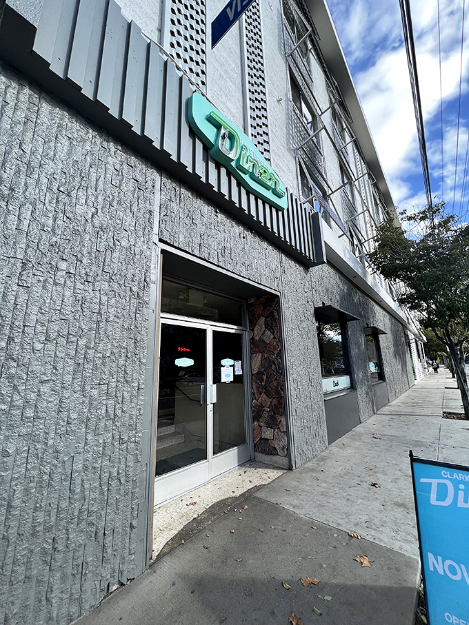 The iconic teal sign of Clark Street Diner beckons from beneath a Hollywood apartment building like a neon promise of comfort food salvation.