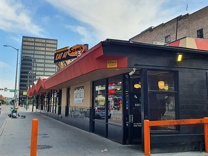 Sam's No. 3 stands proudly with its iconic red awning, a beacon of comfort food amid downtown Denver's glass skyscrapers. Classic diner meets modern city.