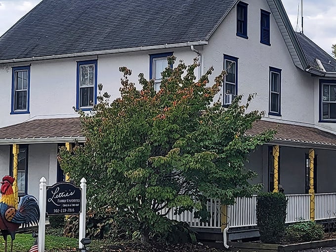 The white farmhouse with blue trim and wrap-around porch isn't trying to be fancy, but that rooster sign is basically saying "chicken paradise ahead!"