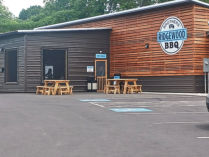 The modern wooden facade of Ridgewood Brothers BBQ stands like a beacon of hope for hungry travelers. Simple picnic tables outside hint at the no-frills focus on what matters most: the meat.