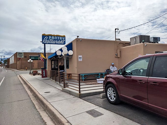The iconic blue Pantry sign stands like a beacon of breakfast hope against the New Mexico sky, promising culinary salvation to hungry souls below.