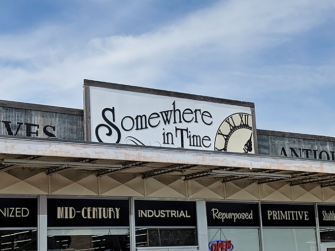 The unassuming storefront of Somewhere In Time beckons with promises of "PRIMITIVES" and "ANTIQUES" – a time portal disguised as a strip mall tenant.