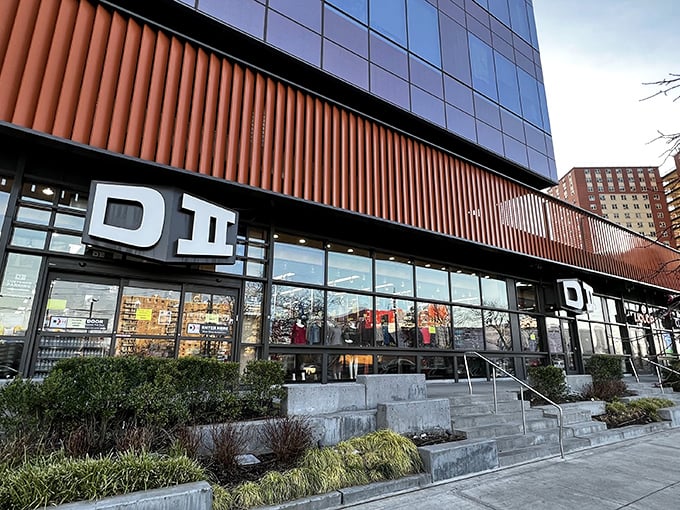 The distinctive orange-trimmed exterior of DII beckons bargain hunters like a retail oasis in Sheepshead Bay, complete with patriotic bunting and clearance promises.
