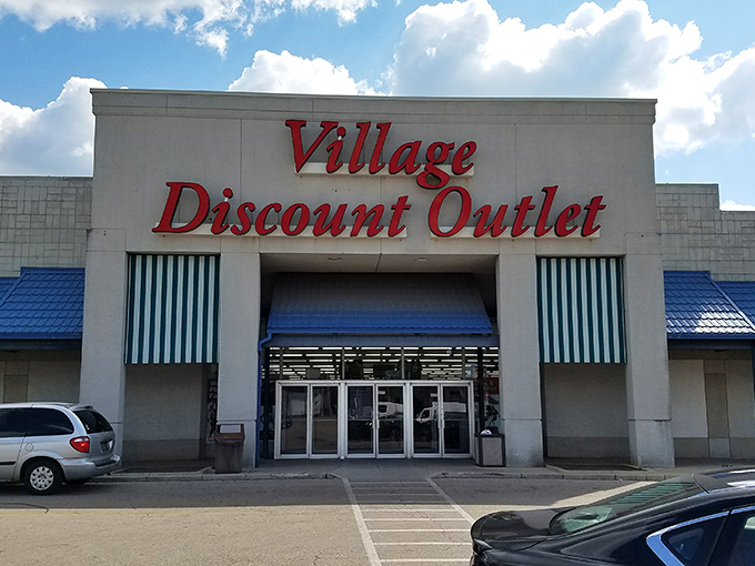 The iconic red signage of Village Discount Outlet beckons like a lighthouse for bargain hunters. Blue awnings and a spacious parking lot welcome treasure seekers of all kinds.