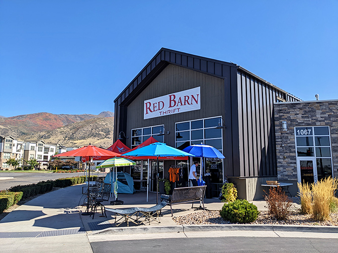 The iconic Red Barn Thrift stands proudly against Utah's mountain backdrop, colorful umbrellas inviting treasure hunters to step inside this Farmington gem.
