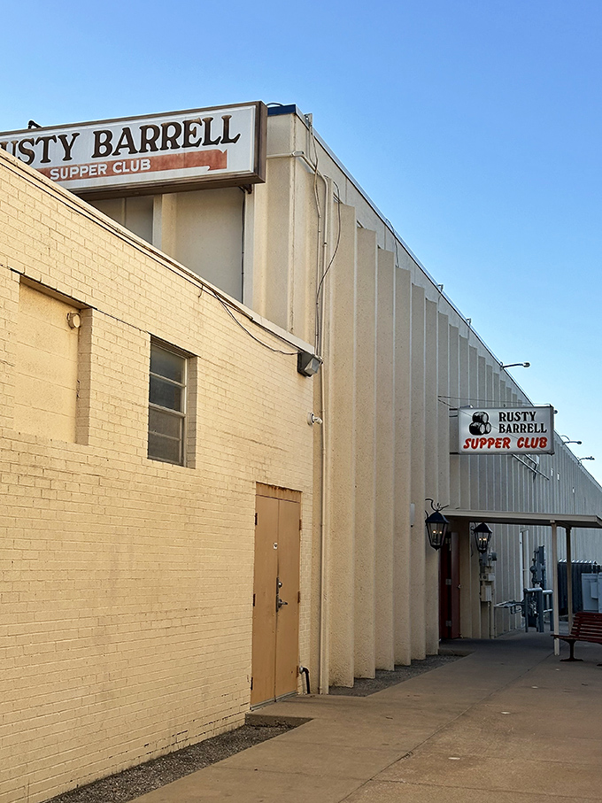 The unassuming entrance to Rusty Barrell Supper Club proves the old adage: never judge a steak by its storefront. That red bench? Your waiting room to carnivore heaven.