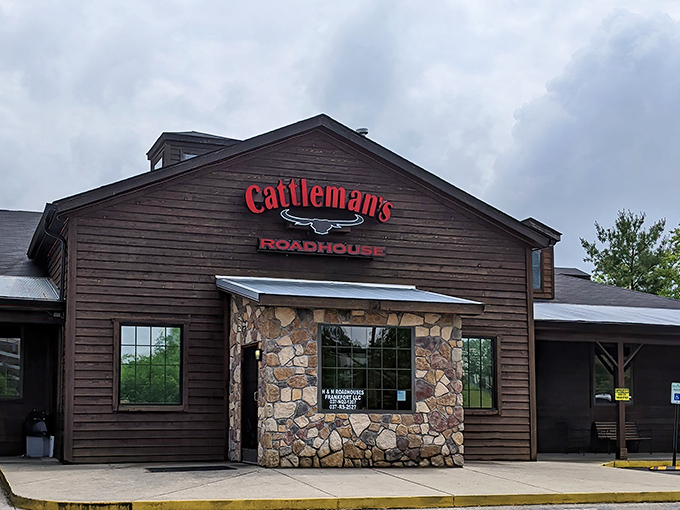 The rustic wooden exterior of Cattleman's Roadhouse beckons like an old friend, promising comfort and satisfaction within those stone-accented walls.