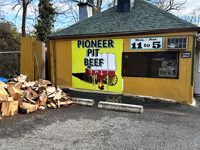 The humble yellow shack with stacked firewood speaks volumes: real pit beef doesn't need fancy digs when the smoke does the talking.