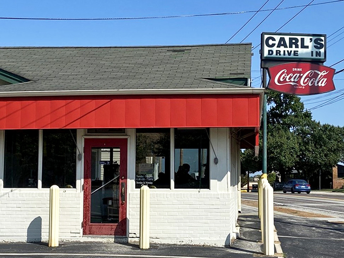 The iconic red and white exterior of Carl's Drive-In stands as a time capsule on Manchester Road, complete with its vintage Coca-Cola sign that's been guiding hungry travelers since the 1950s.