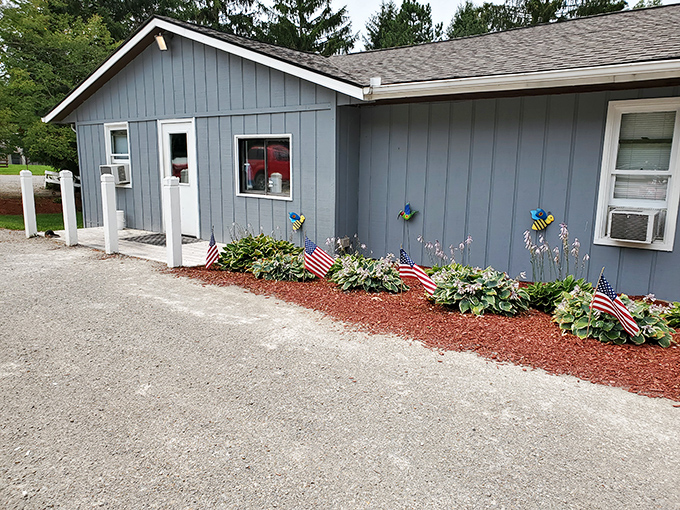 The iconic orange sign beckons hungry travelers like a burger lighthouse. This unassuming blue building houses flavor treasures worth the drive.