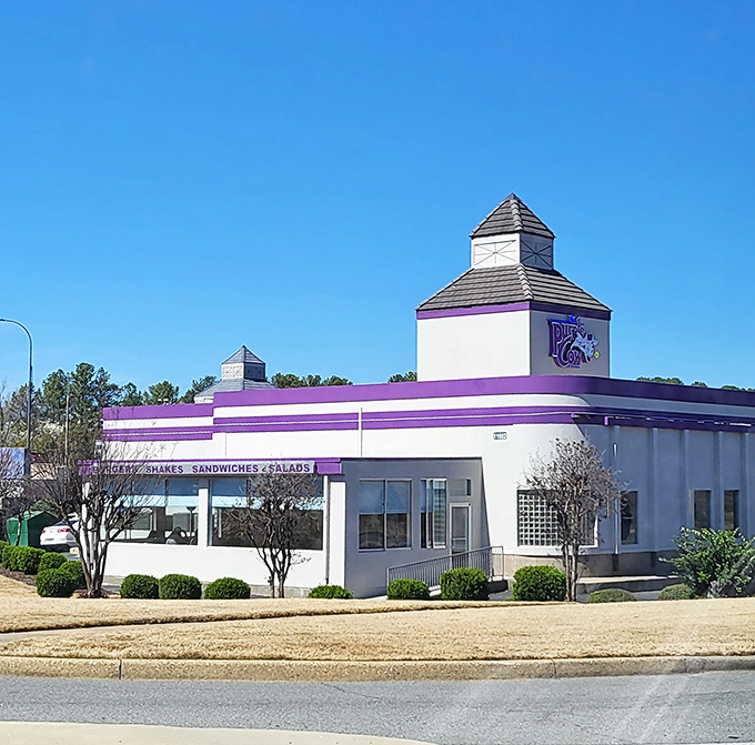 The streamlined Art Deco exterior of The Purple Cow stands like a time machine to the 1950s, promising nostalgic delights within its crisp white walls.