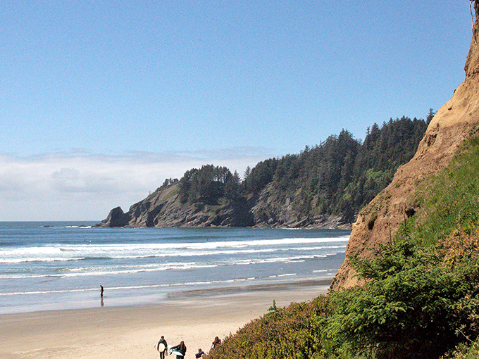 Golden sands meet dramatic cliffs where surfers catch perfect waves beneath an impossibly blue Oregon sky. Mother Nature showing off again.