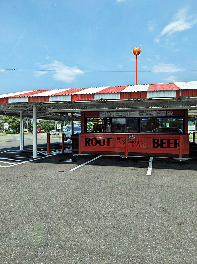 The iconic red and white striped canopy of Stewart's Drive-In stands like a time capsule on wheels, beckoning hungry travelers with promises of nostalgia and root beer.