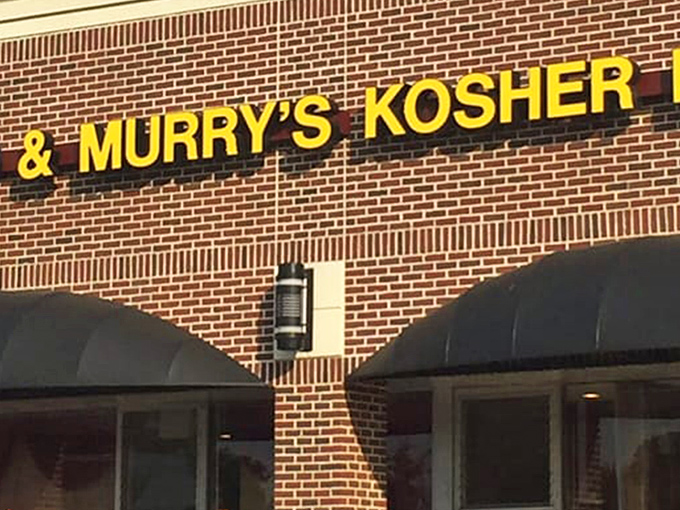 The Promised Land of pastrami sits quietly in a strip mall, its yellow sign a beacon to hungry souls seeking deli salvation.