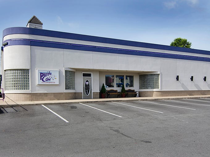 The streamlined Art Deco exterior of The Purple Cow stands like a time machine to the 1950s, promising nostalgic delights within its crisp white walls.