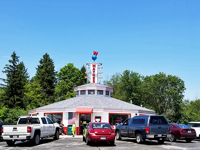 The unmistakable silhouette of Wayne's Drive-In stands against a perfect Wisconsin sky, its iconic neon sign promising burger bliss to all who approach.