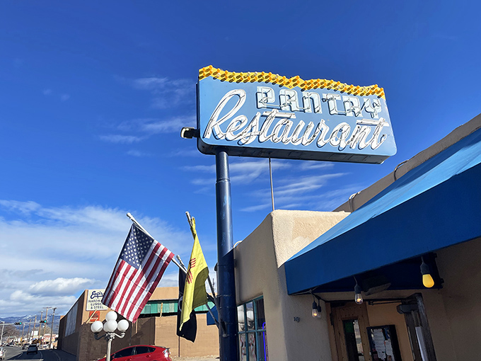 The iconic blue Pantry sign stands like a beacon of breakfast hope against the New Mexico sky, promising culinary salvation to hungry souls below.