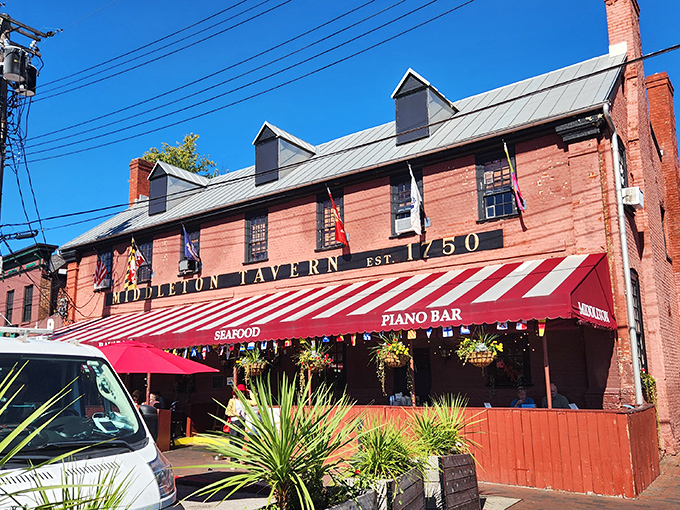 The historic red brick facade of Middleton Tavern stands proudly since 1750, its striped awning beckoning like a culinary time machine to colonial Annapolis.