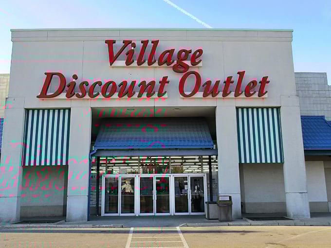 The iconic red signage of Village Discount Outlet beckons like a lighthouse for bargain hunters. Blue awnings and a spacious parking lot welcome treasure seekers of all kinds.