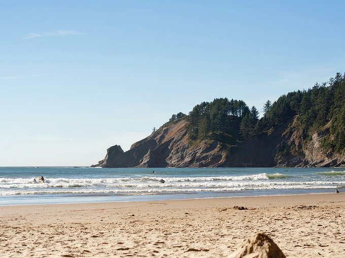Golden sands meet dramatic cliffs where surfers catch perfect waves beneath an impossibly blue Oregon sky. Mother Nature showing off again.