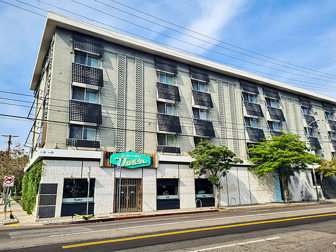 The iconic teal sign of Clark Street Diner beckons from beneath a Hollywood apartment building like a neon promise of comfort food salvation.