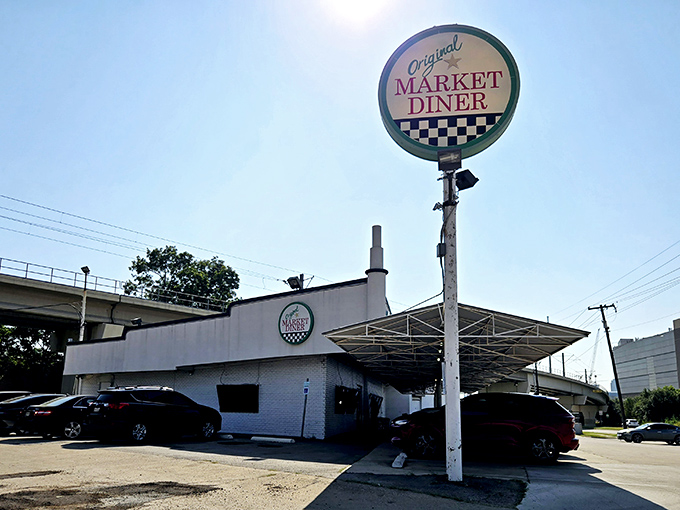 The iconic green and white signage promises comfort food salvation, standing defiantly against Dallas's modernizing skyline.