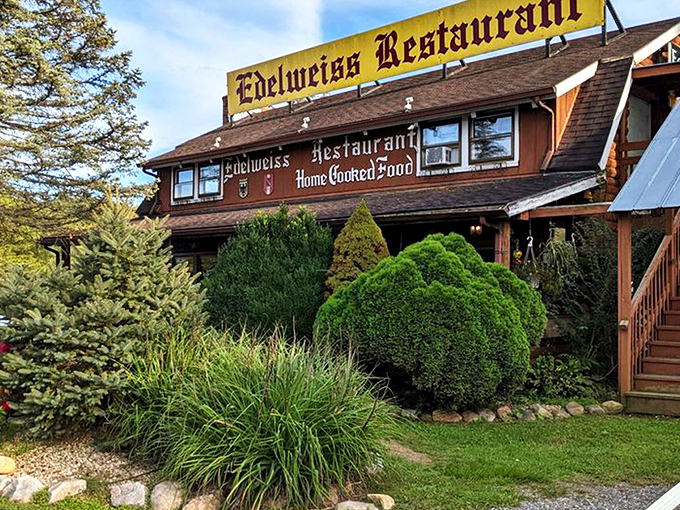 The rustic log cabin exterior of Edelweiss Restaurant promises Bavarian delights beneath stormy skies. Like finding a German postcard come to life in Virginia's Shenandoah Valley.