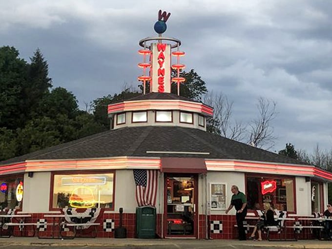 The unmistakable silhouette of Wayne's Drive-In stands against a perfect Wisconsin sky, its iconic neon sign promising burger bliss to all who approach.