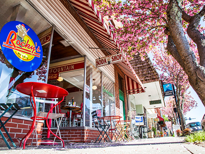 Cherry blossoms frame Rocky's iconic storefront like nature's own welcome sign, complete with those irresistible red sidewalk tables beckoning passersby.