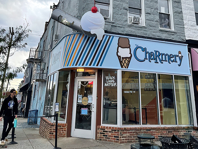 The corner shop that launched a thousand cravings. The Charmery's blue-striped awning and iconic ice cream cone logo beckon from Hampden's bustling Avenue.