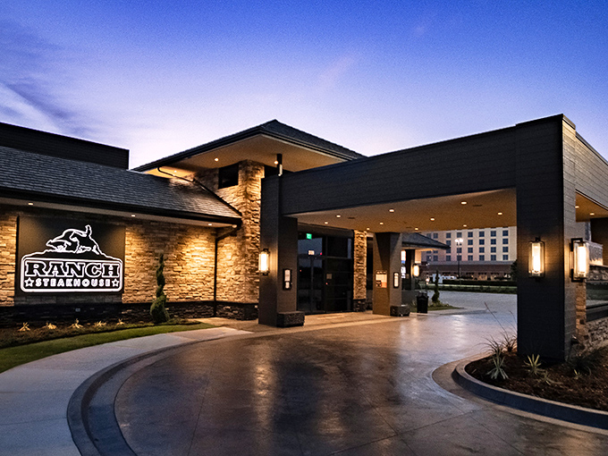 The modern stone facade of Ranch Steakhouse stands confidently against the Oklahoma sky, like a culinary fortress promising delicious treasures within.