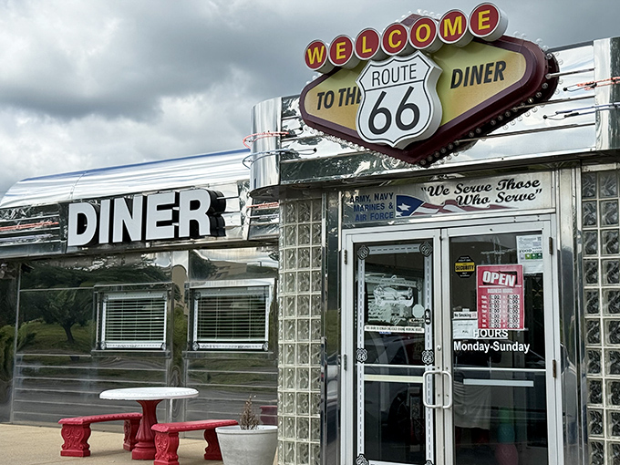That iconic sign beckons like a chrome-clad siren song from the roadside, promising a journey back to when highways meant adventure, not just commutes.