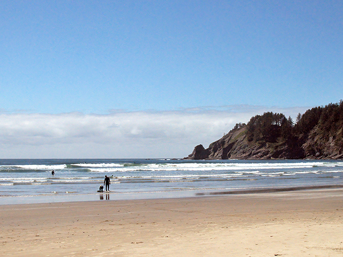 Golden sands meet dramatic cliffs where surfers catch perfect waves beneath an impossibly blue Oregon sky. Mother Nature showing off again.