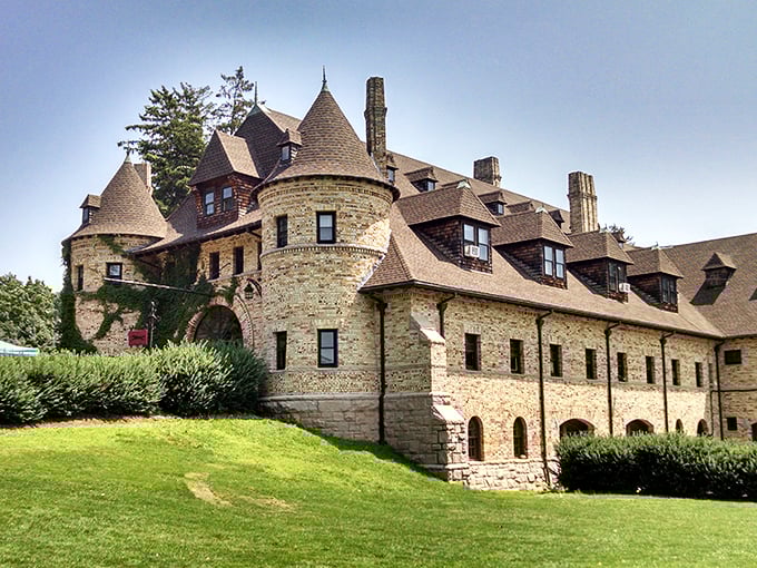 The castle-like exterior of Larz Anderson Auto Museum stands majestically against a blue sky, while a modern yellow Porsche offers a striking contrast to the historic stone facade.