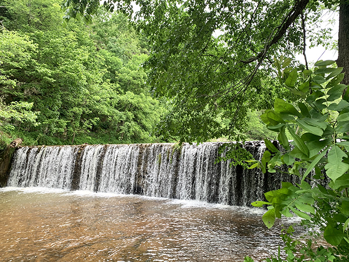 Nature's perfect curtain call &ndash; water cascades over a wide ledge, creating a serene backdrop that makes even smartphone photographers look like Ansel Adams.