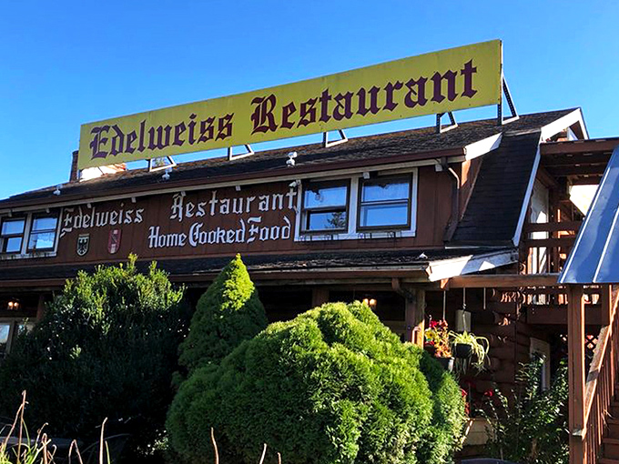 The rustic log cabin exterior of Edelweiss Restaurant promises Bavarian delights beneath stormy skies. Like finding a German postcard come to life in Virginia's Shenandoah Valley.
