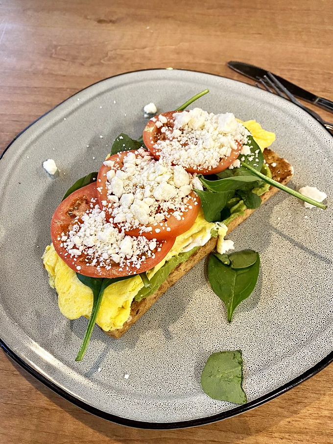 Avocado toast that transcends trendy—perfectly ripened fruit, tomato slices, feta crumbles, and just the right amount of greenery on artisanal bread.