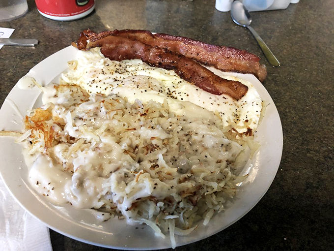 Hash browns smothered in country gravy with bacon standing at attention. A breakfast plate that demands to be saluted.