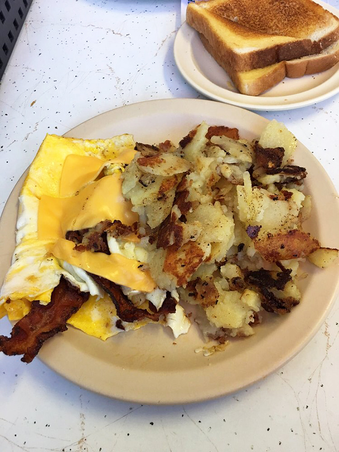 Toast stands by like a faithful sidekick while eggs and hash browns do the heavy lifting of breakfast satisfaction. Simple perfection on a white plate.