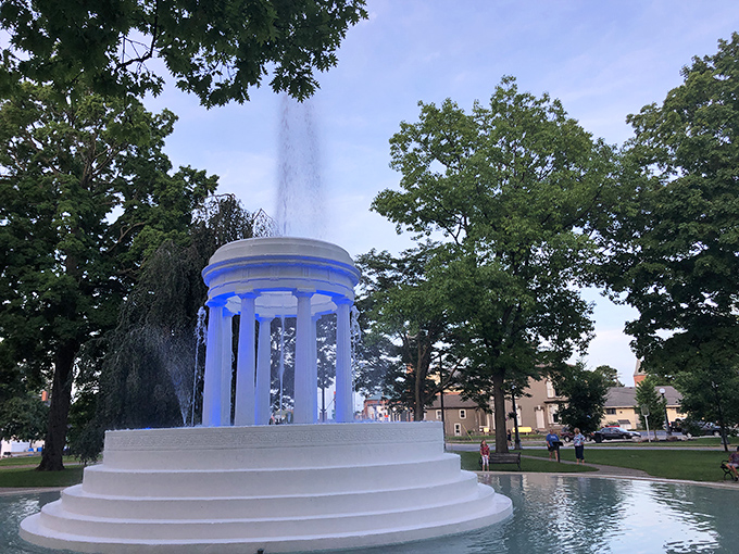 The Brooks Memorial Fountain glows ethereally at dusk, its classical columns and dancing waters creating a moment of unexpected elegance in small-town Michigan.