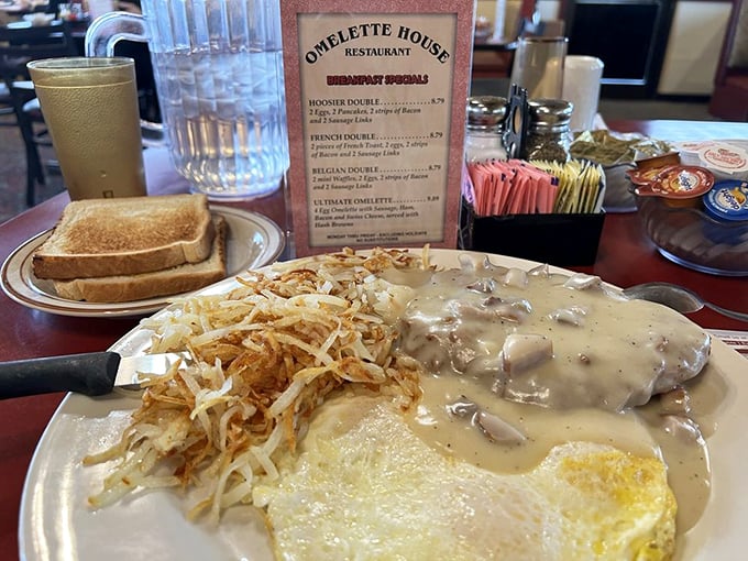 Country gravy cascading over comfort food like a warm hug from the inside out. Those hash browns are the crispy wingmen every breakfast deserves.